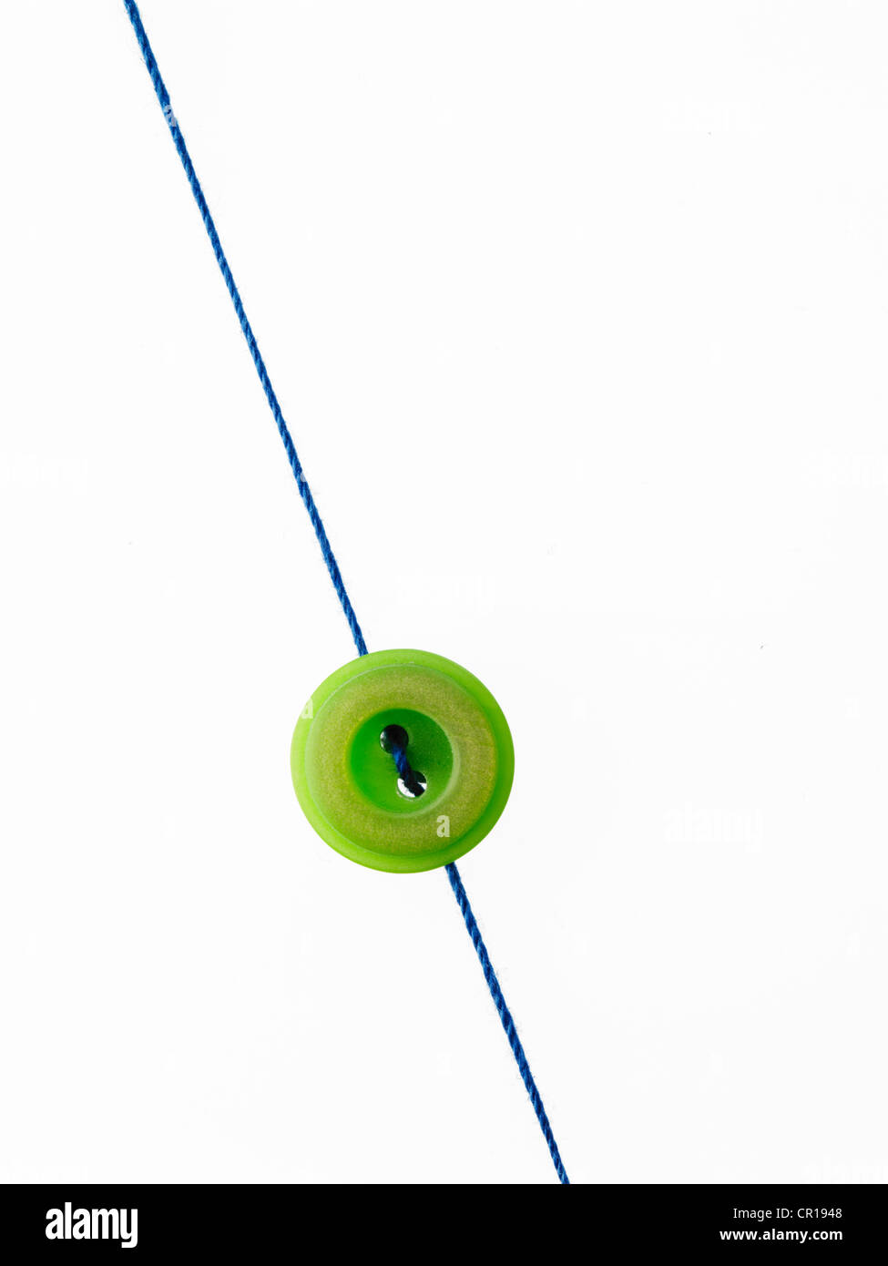 Studio shot of single green button on thread Stock Photo - Alamy