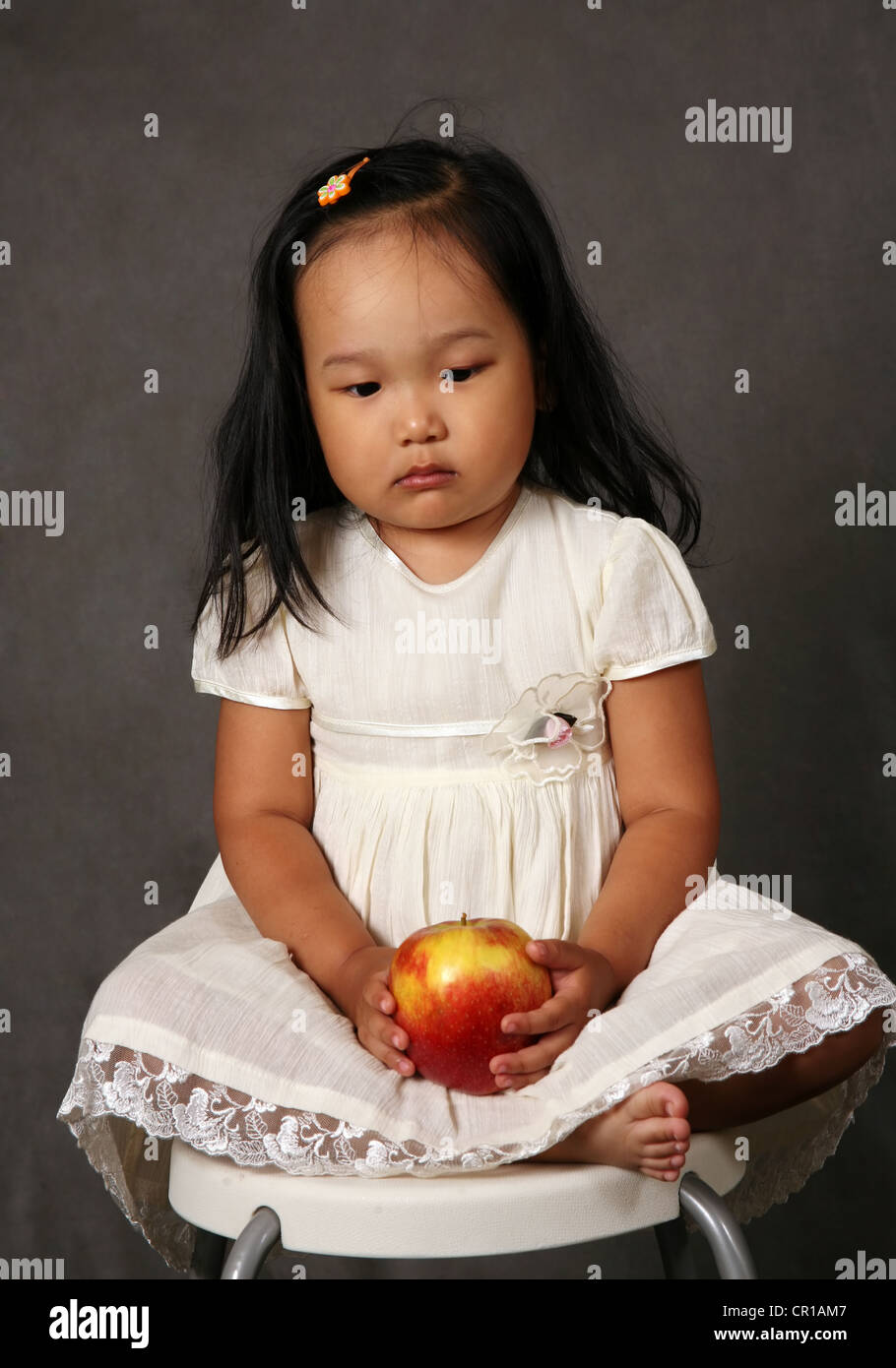The small Korean girl with apple in studio Stock Photo - Alamy