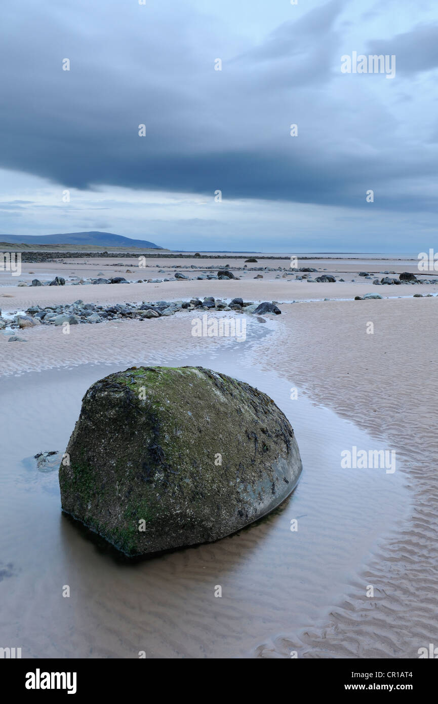 A boulder sat in a pool of water on the beach at Seascale, Cumbria, UK ...