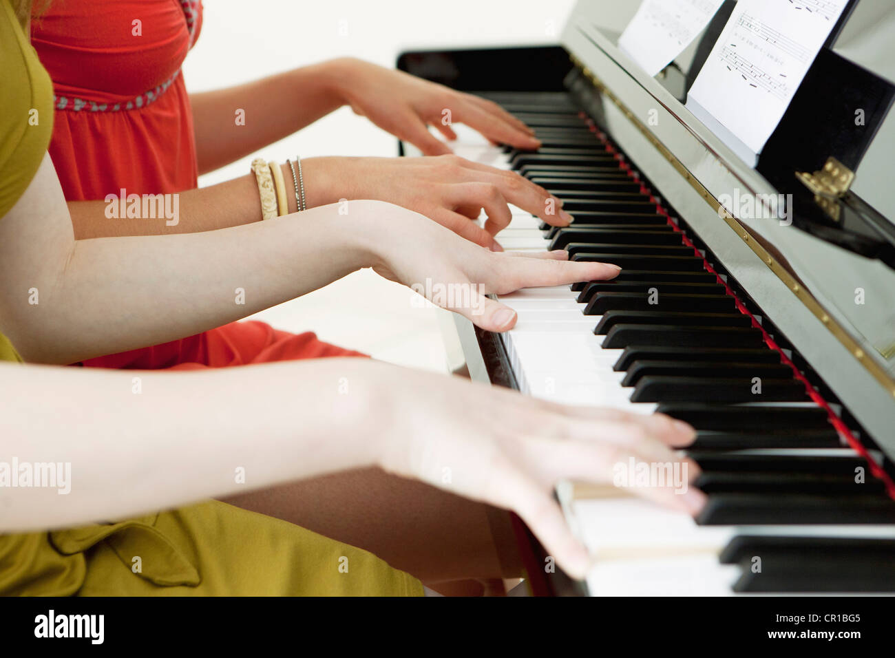 Teenage girls playing piano together Stock Photo - Alamy