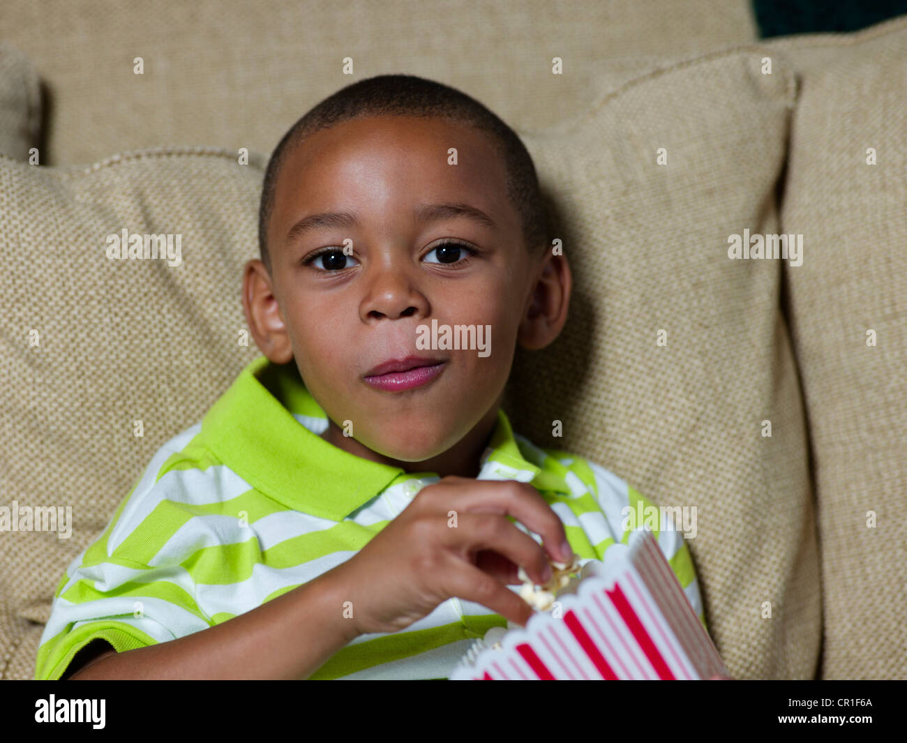 Boy eating popcorn on couch Stock Photo - Alamy