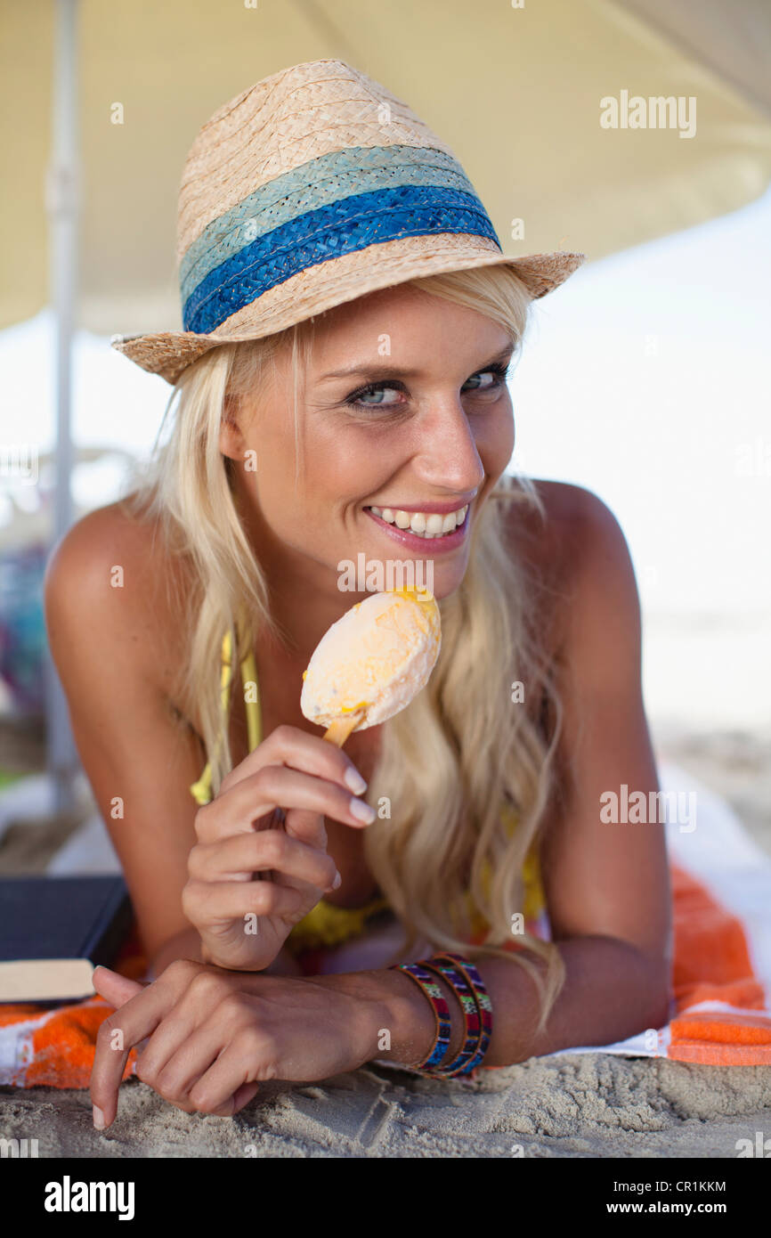 Smiling woman eating popsicle on beach Stock Photo - Alamy