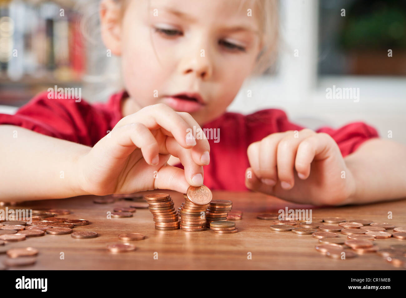 Girl playing with pennies at table Stock Photo - Alamy