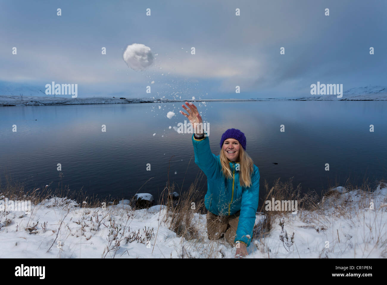 Woman throwing snowball by lake Stock Photo - Alamy