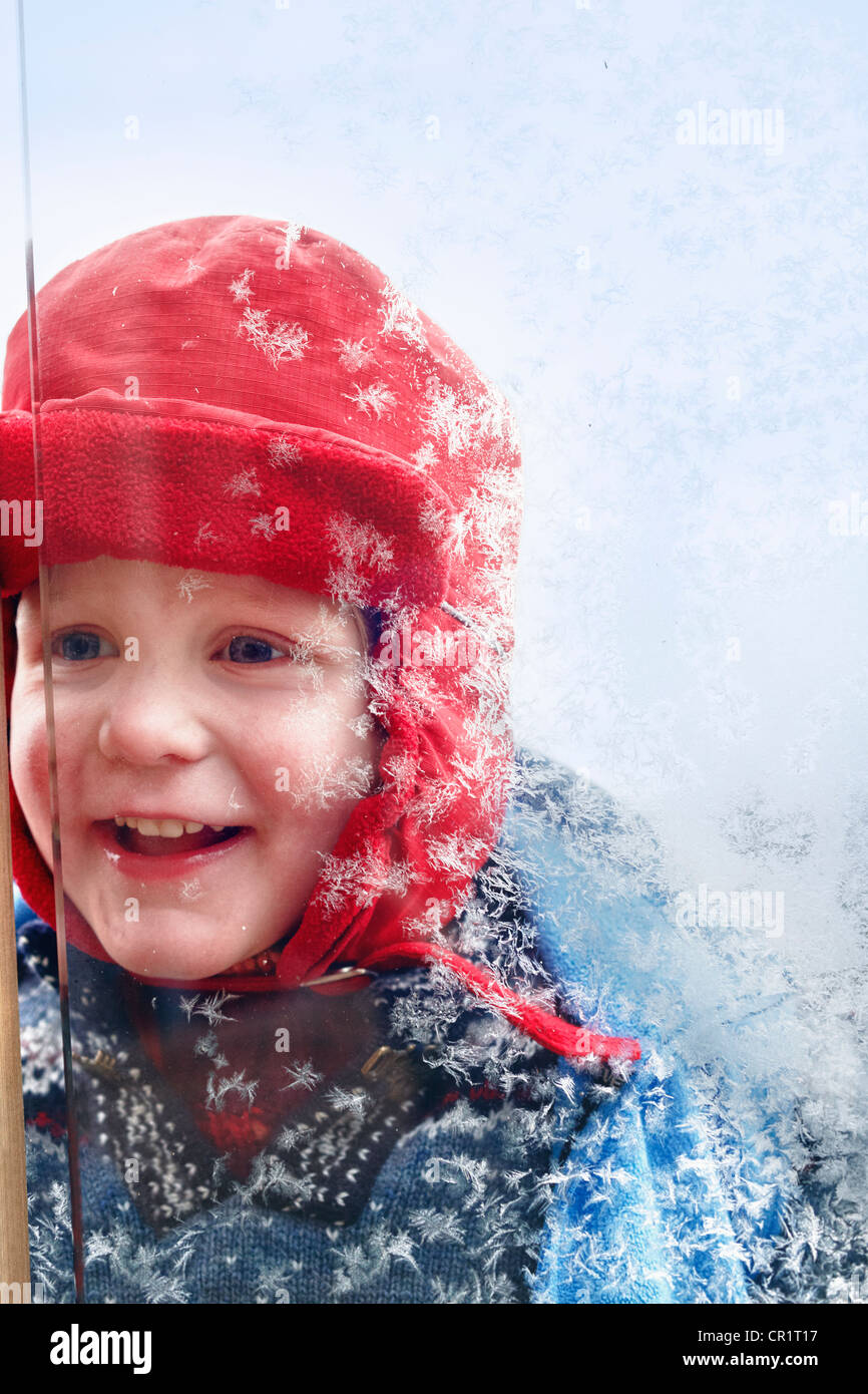Smiling boy looking in frosty window Stock Photo - Alamy
