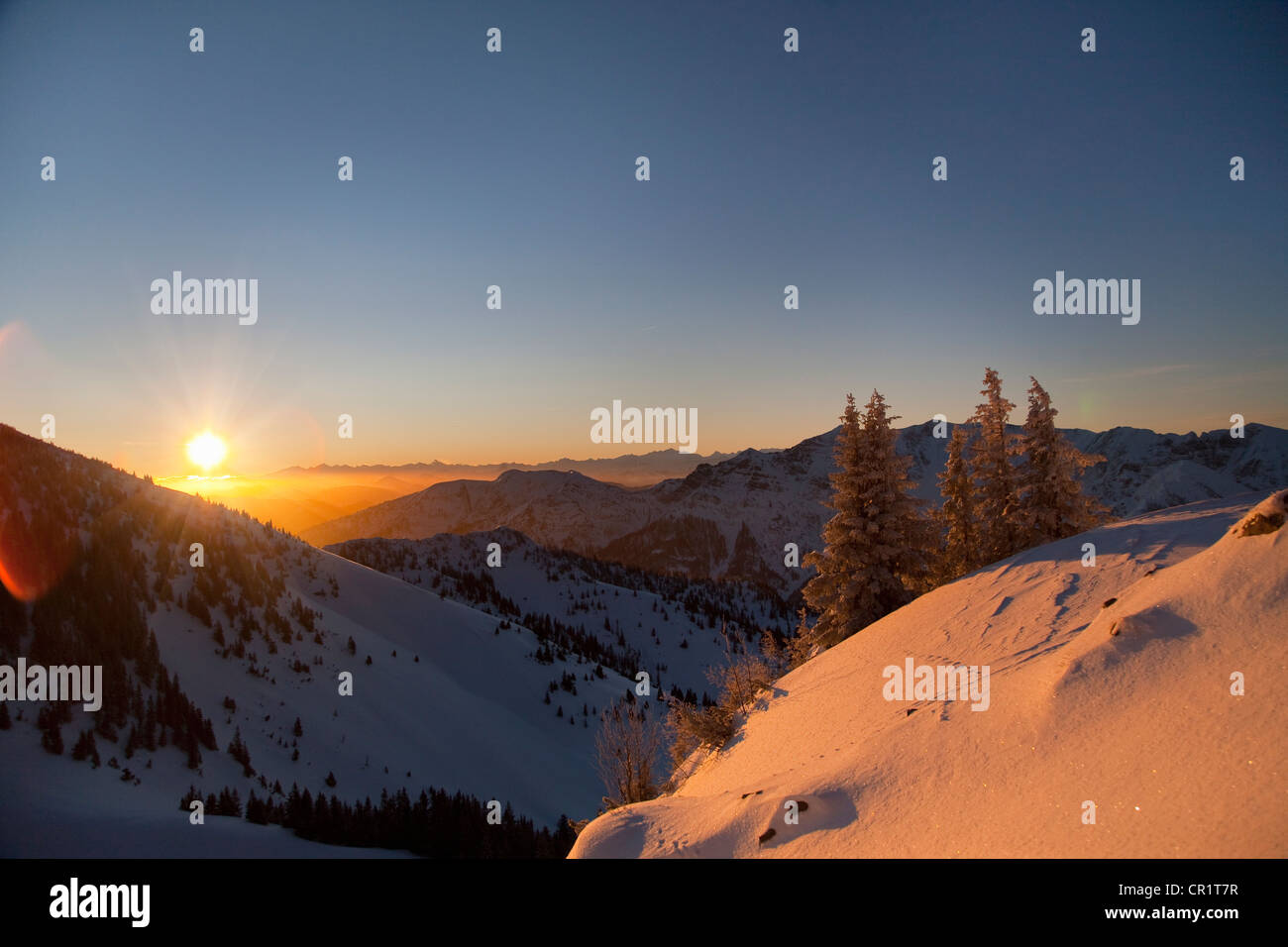 Sun setting over snowy landscape Stock Photo - Alamy