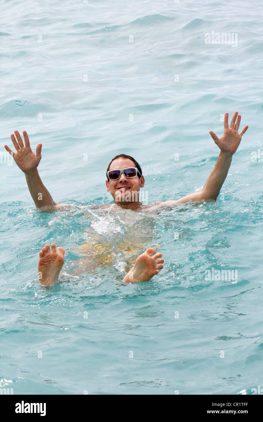 Man floating in water in a lagoon, hand held high, Maldives, Indian ...