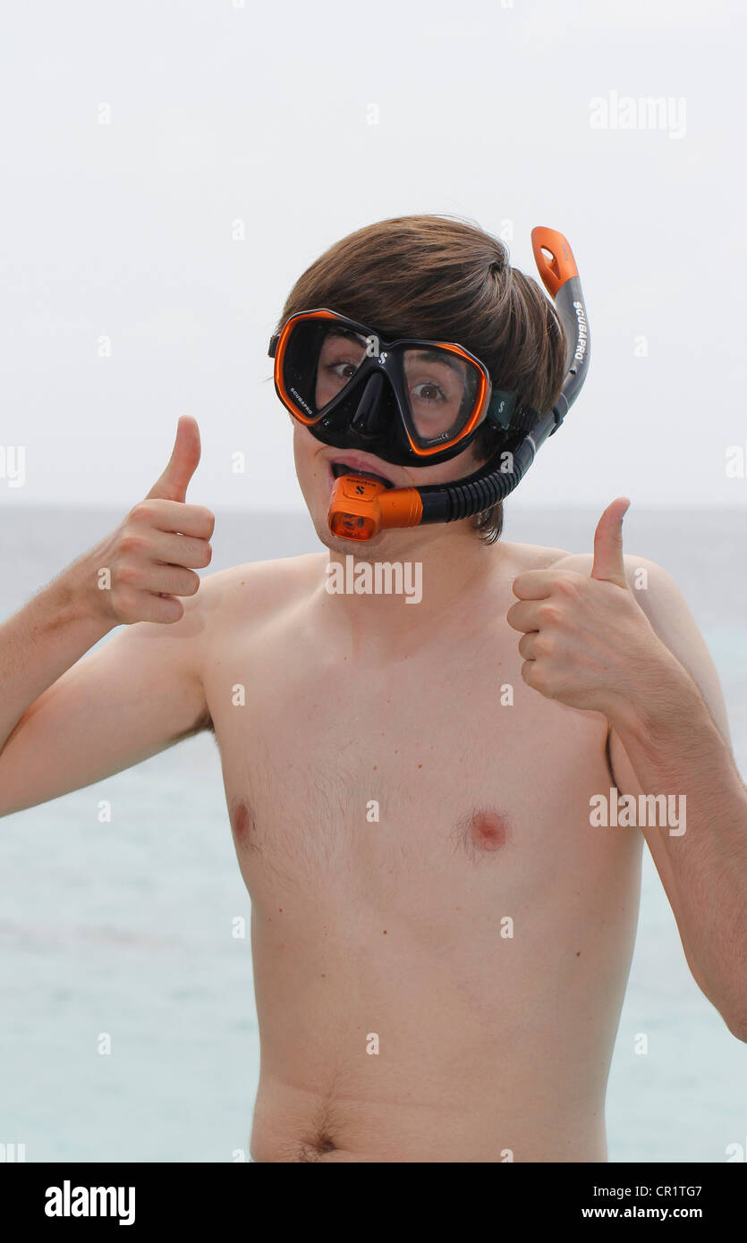 Young man wearing snorkel and diving goggles, thumbs up gesture ...