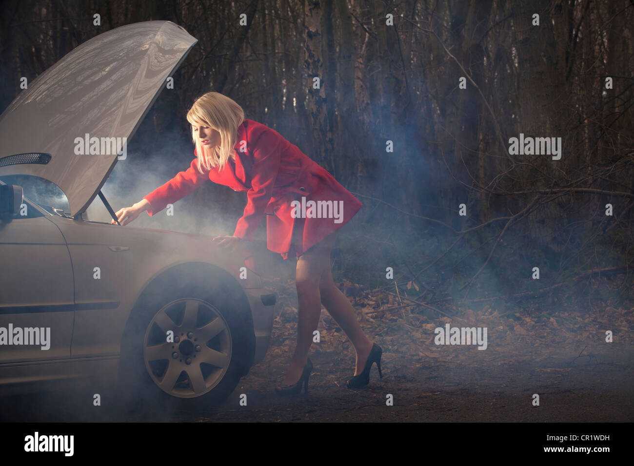 Woman looking under hood of car at night Stock Photo - Alamy