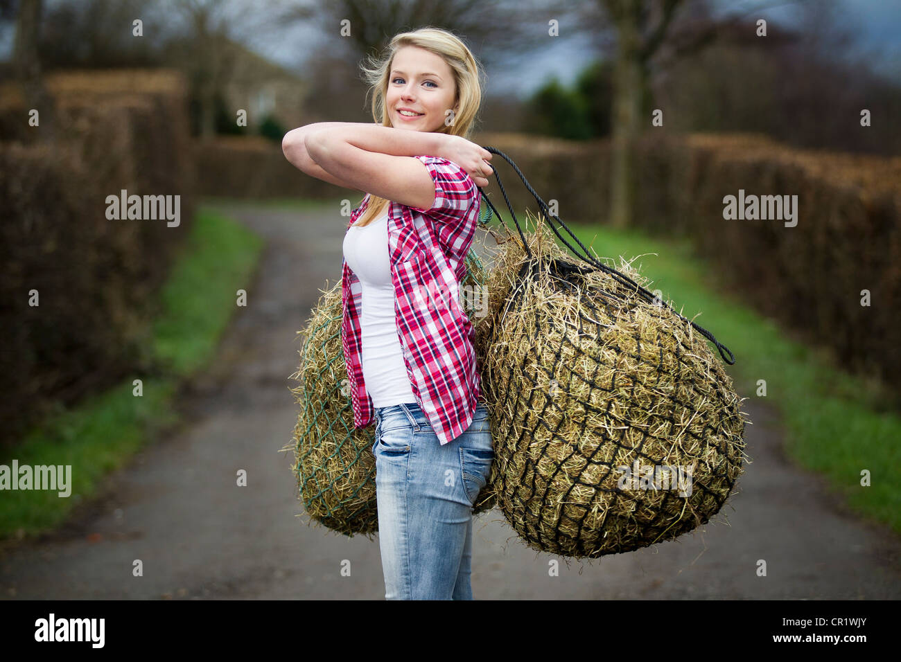 Teenage girl carrying hay on dirt path Stock Photo - Alamy