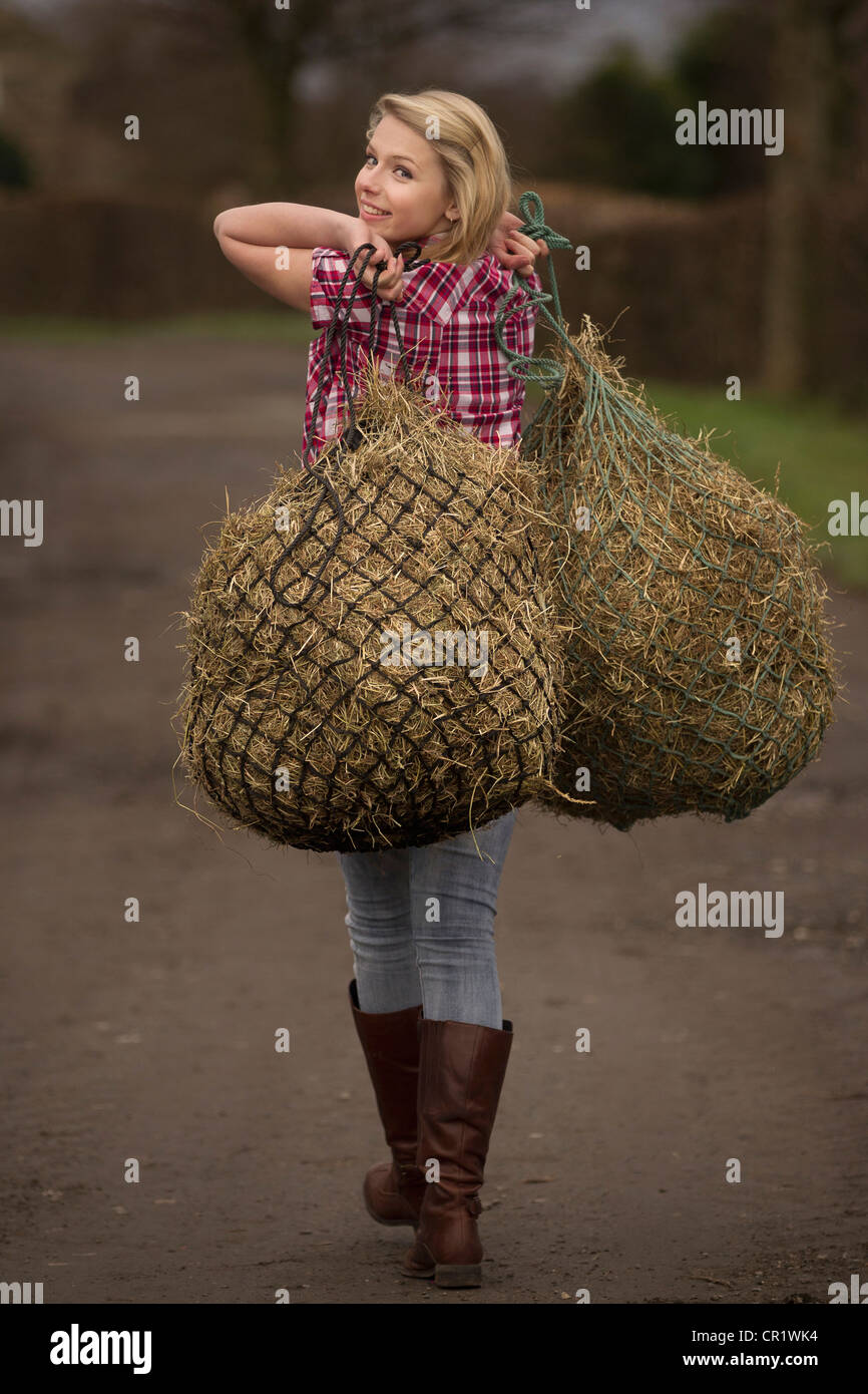 Teenage girl carrying hay on dirt path Stock Photo - Alamy