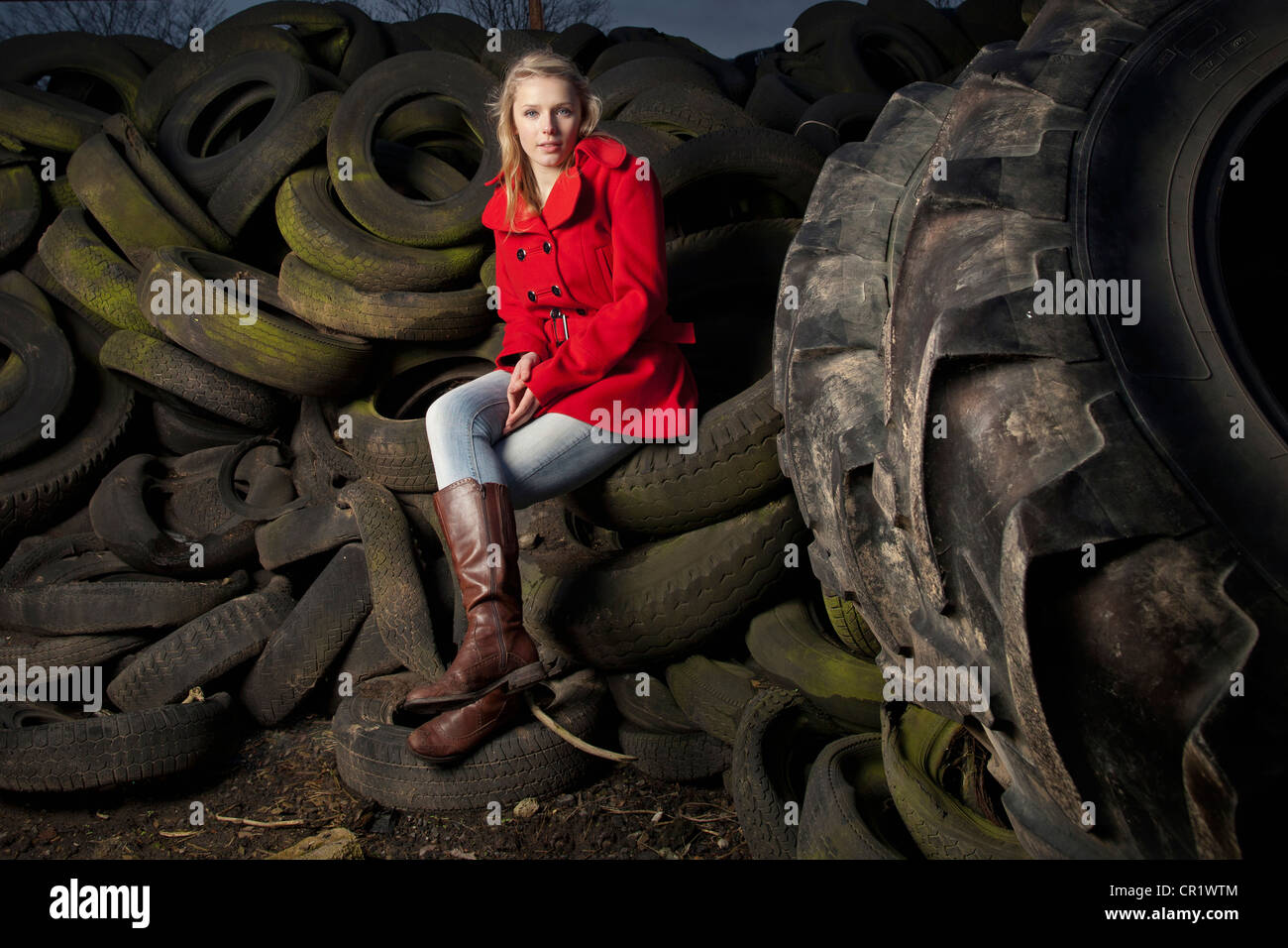 Teenage girl sitting on discarded tires Stock Photo - Alamy