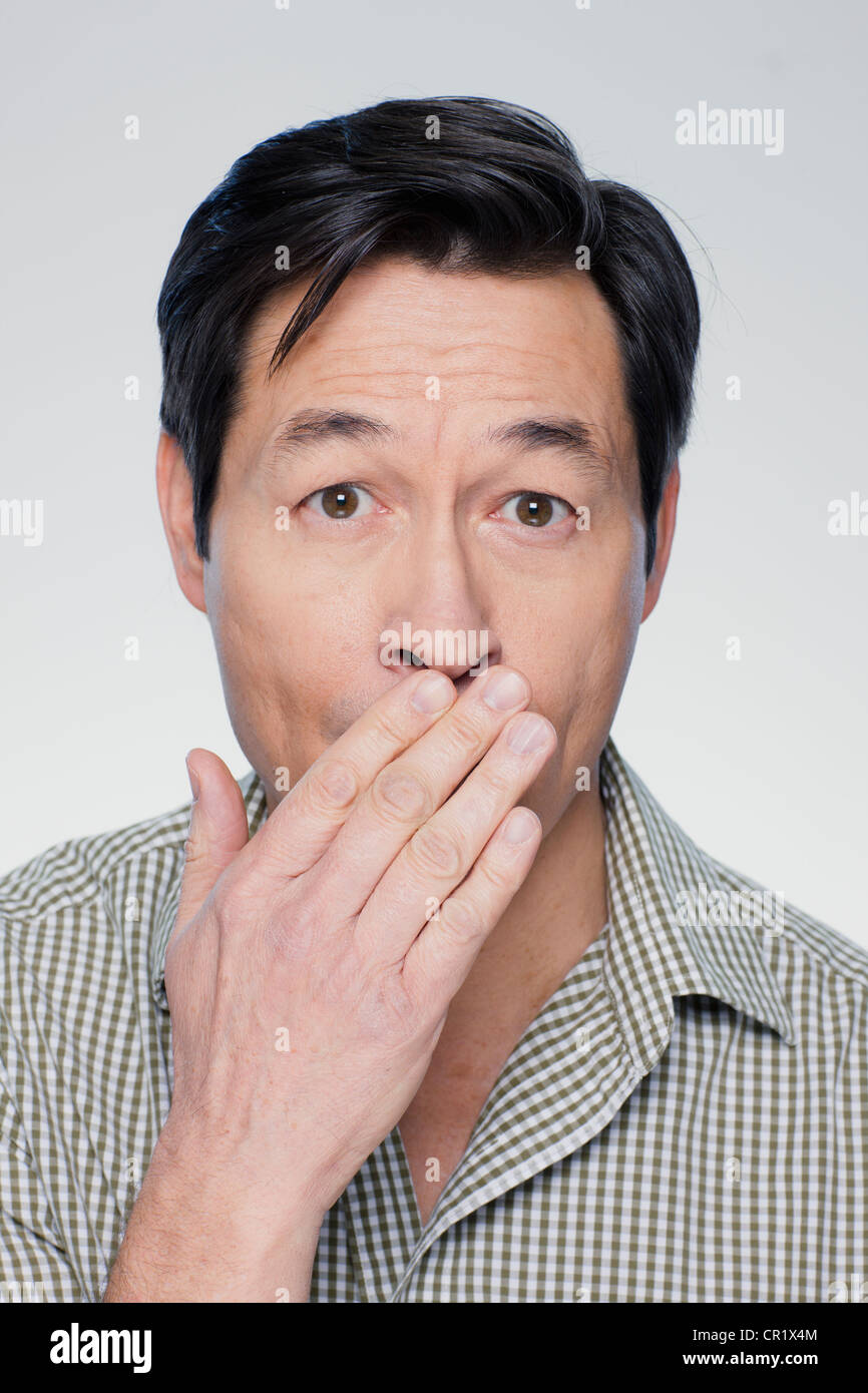 Studio portrait of mature man covering mouth Stock Photo - Alamy