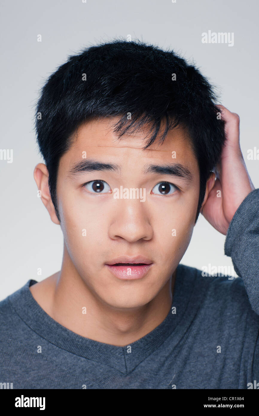 Studio portrait of young man scratching head Stock Photo - Alamy