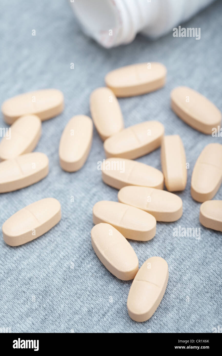 Many pills near white container. Close-up photo Stock Photo - Alamy