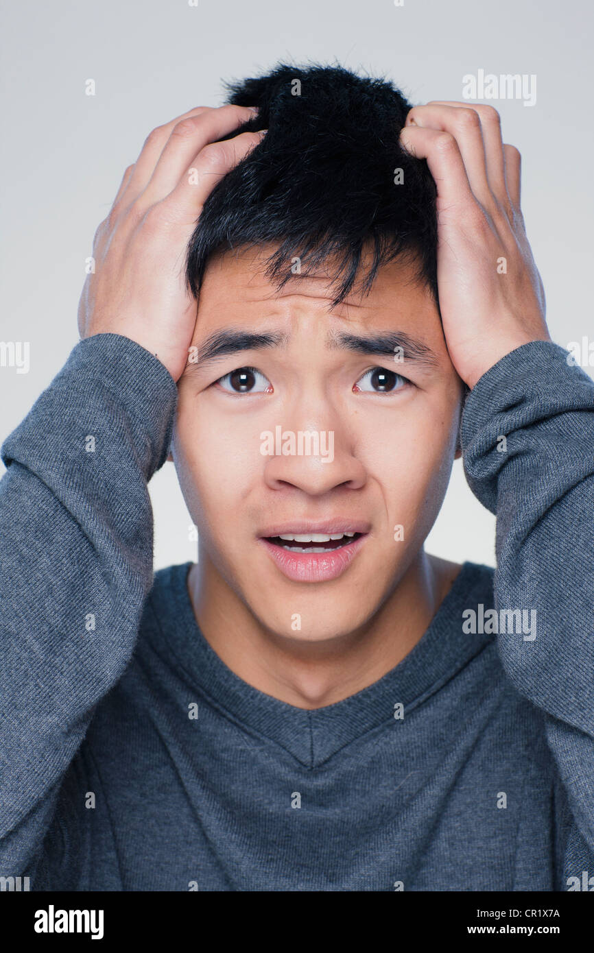 Studio portrait of young man with head in hands Stock Photo - Alamy