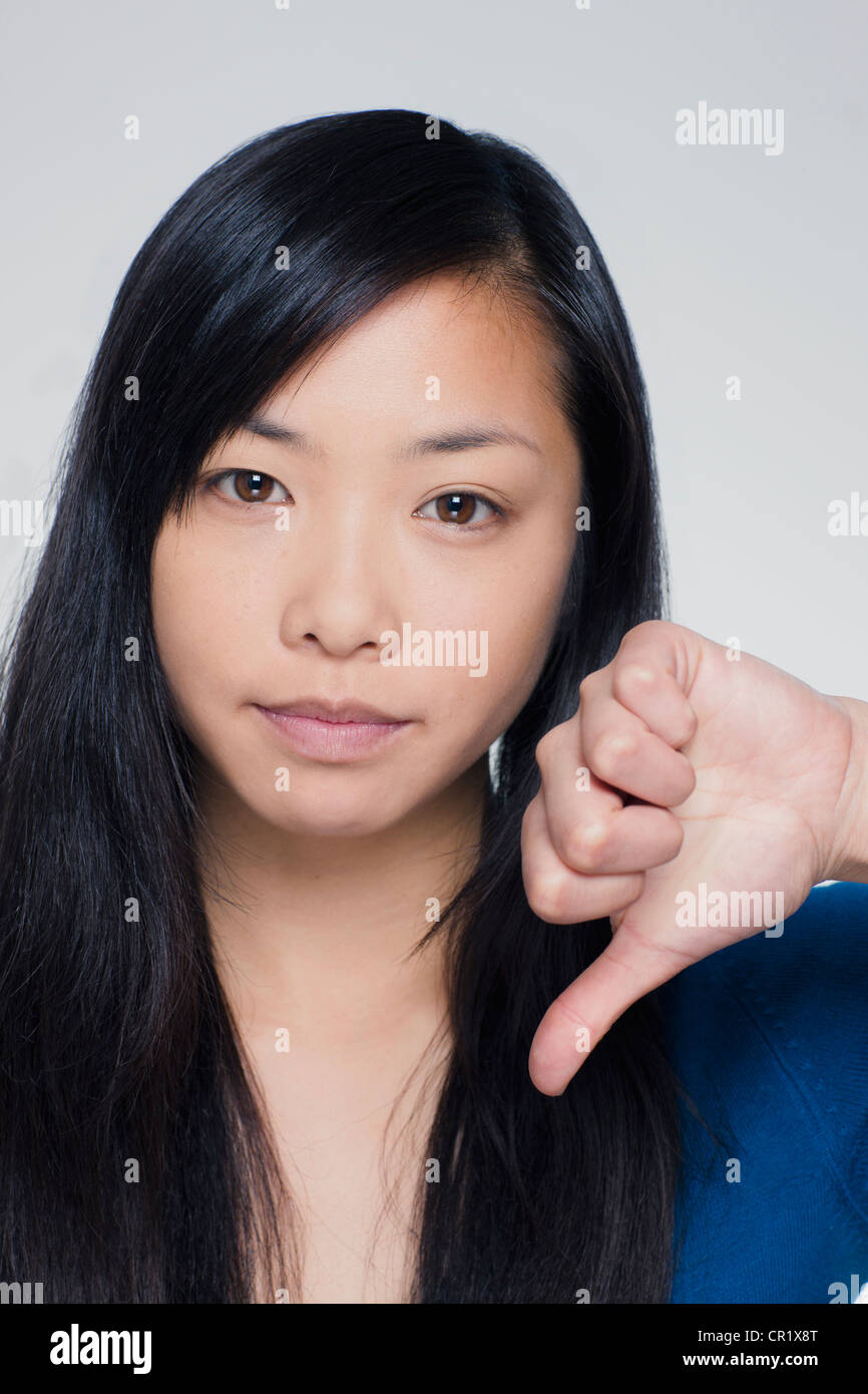Studio portrait of young woman showing thumbs down sign Stock Photo - Alamy