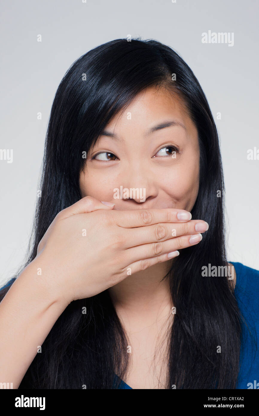 Studio portrait of young woman covering mouth Stock Photo - Alamy