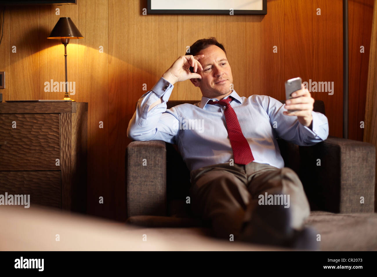 Businessman on cell phone in hotel room Stock Photo - Alamy