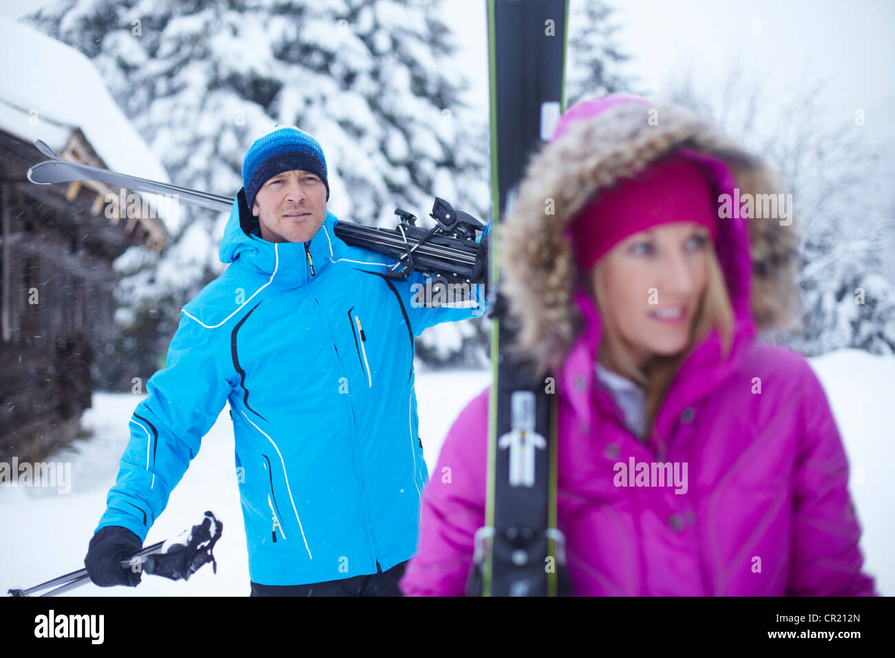 Couple carrying skis and poles in snow Stock Photo - Alamy