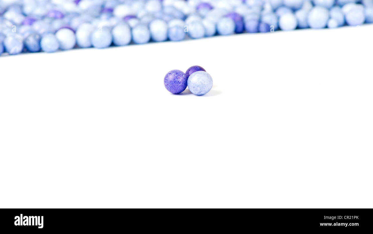 One blue and two violet little pearls isolated on background of other ...