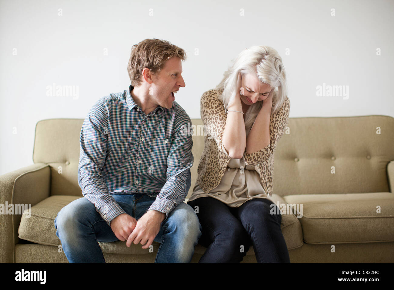 Young couple arguing while sitting on sofa Stock Photo - Alamy