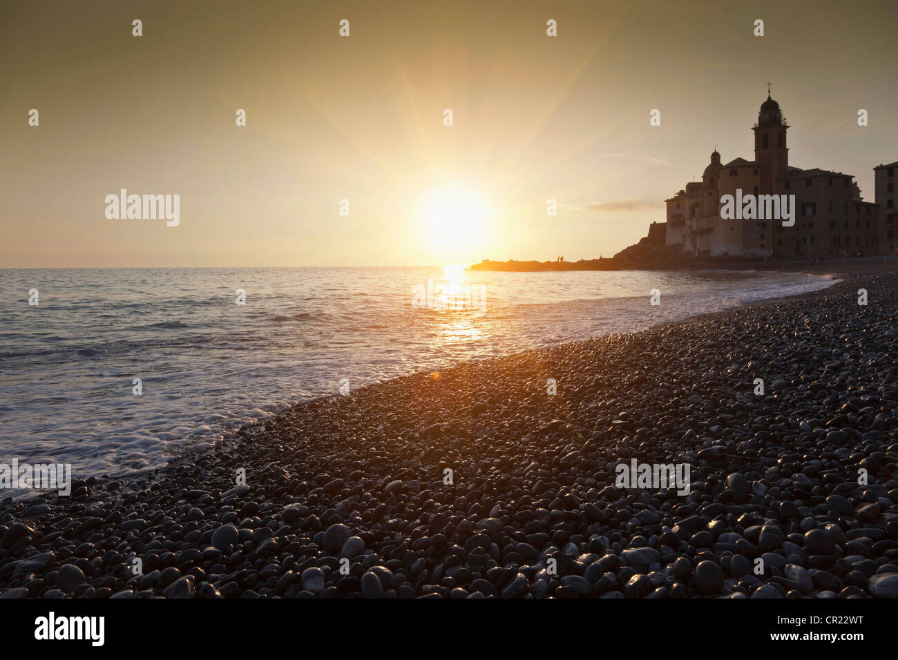 Sun setting over rocky beach Stock Photo - Alamy