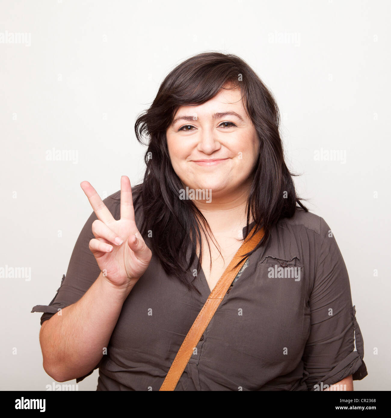 Studio Shot of young woman making Peace Sign Stock Photo - Alamy