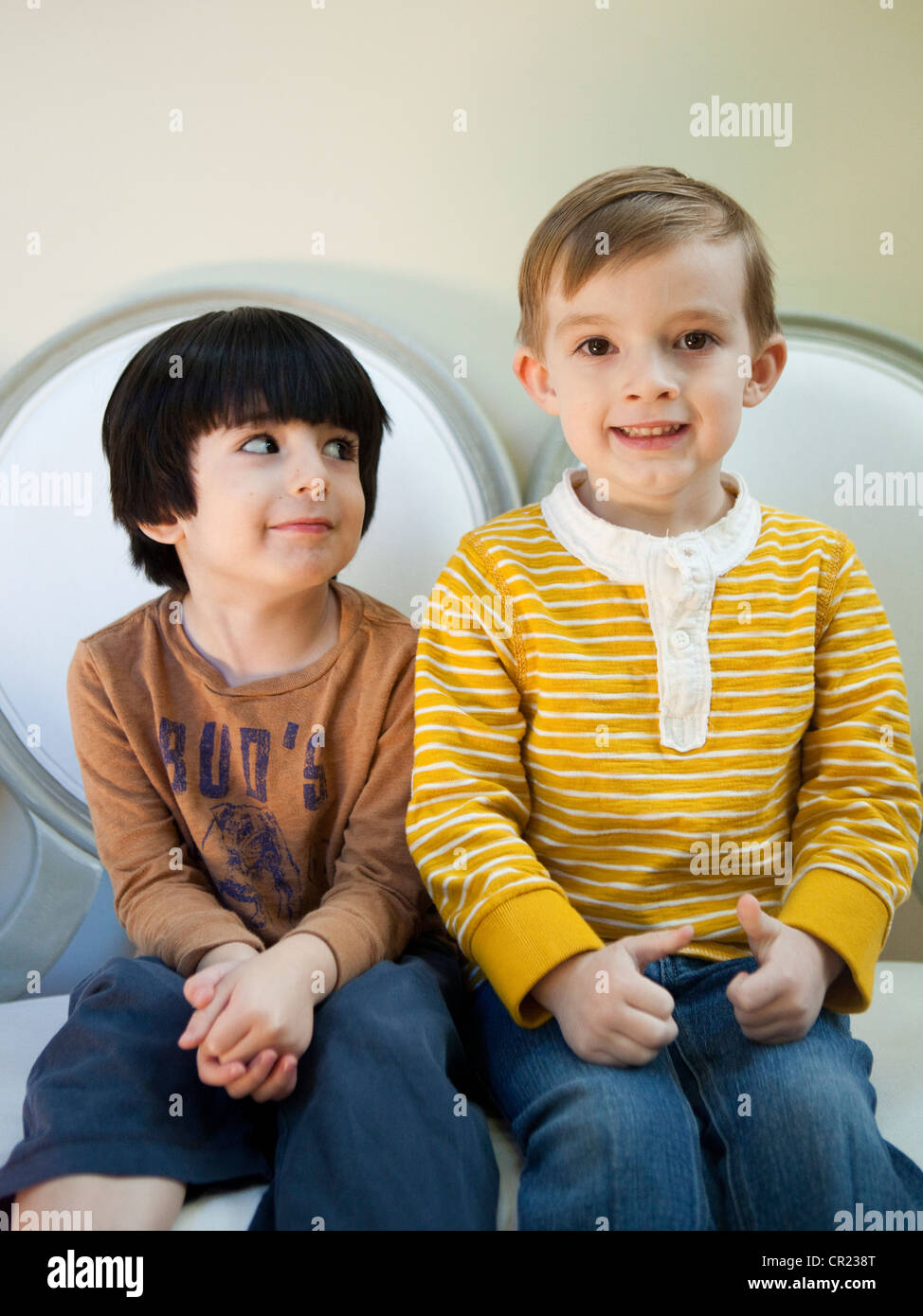 Studio Shot portrait of two boys (4-5, 6-7) sitting side by side Stock ...