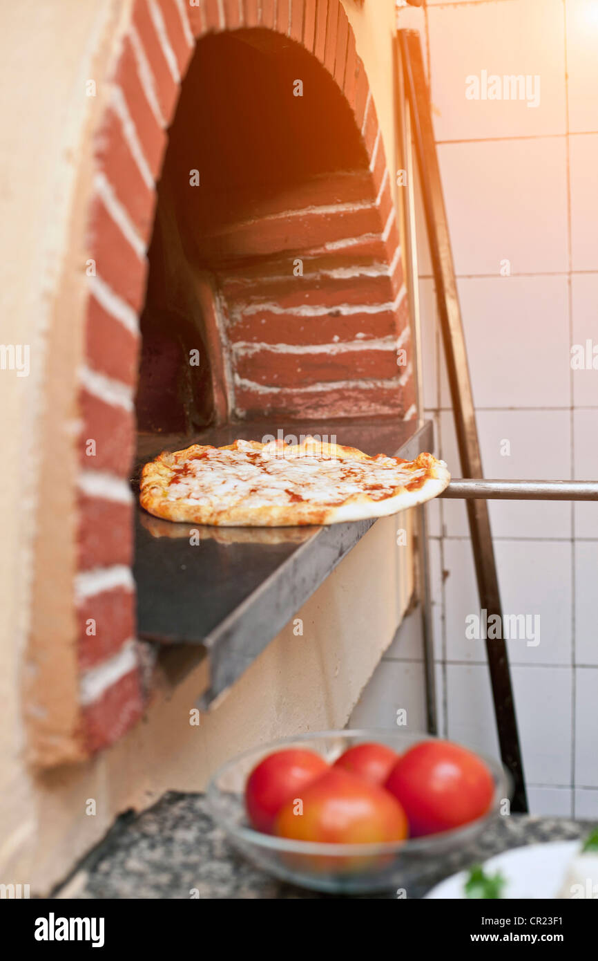 Chef pulling pizza from oven Stock Photo - Alamy