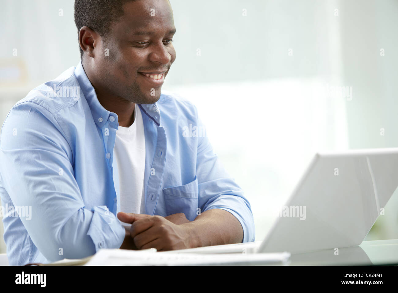 Image of young African businessman looking at laptop screen at ...