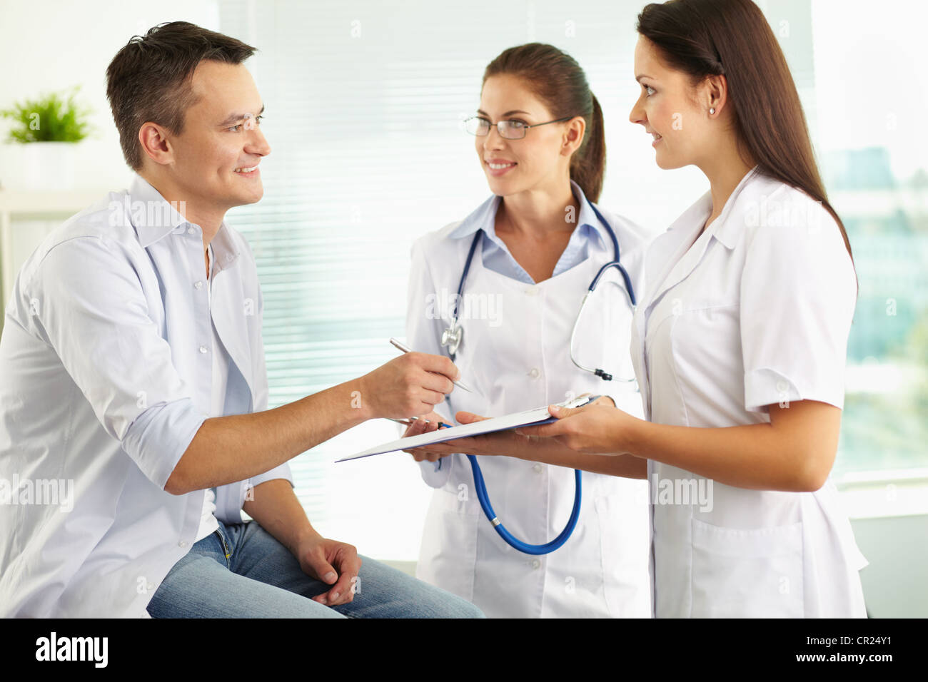 Handsome male patient signing the form given to him by the doctor Stock ...