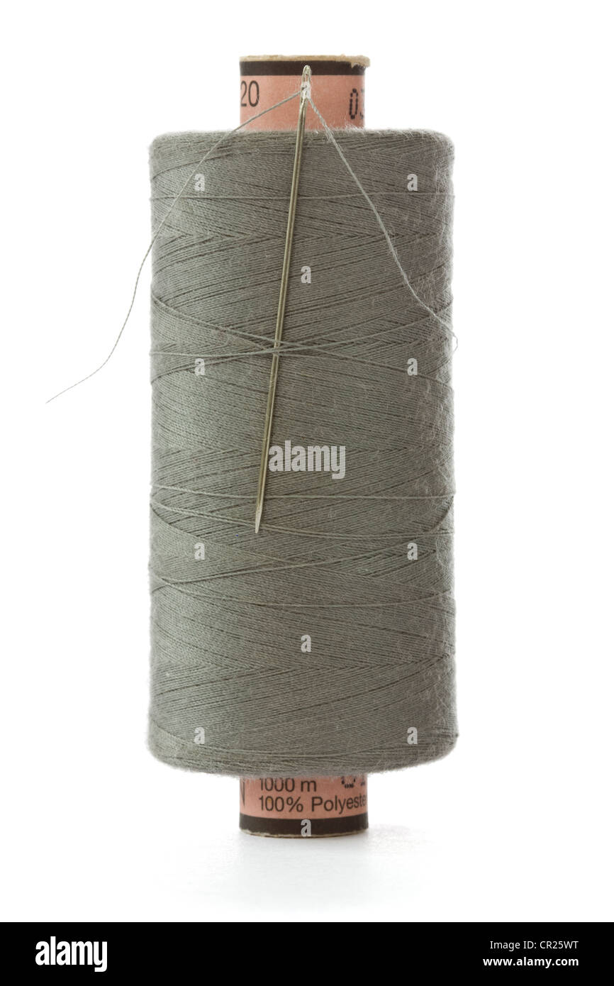 grey bobbin thread with a needle on white background Stock Photo - Alamy