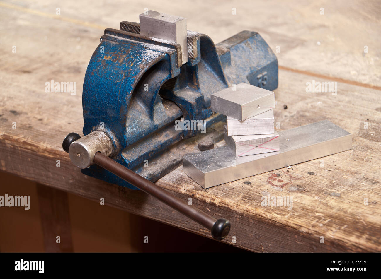 Vice with a block of metal on a wooden workbench Stock Photo - Alamy