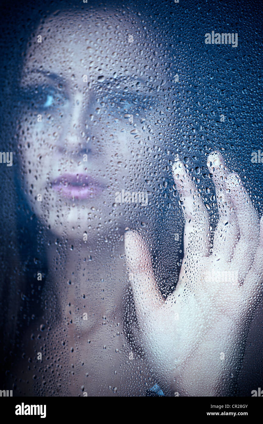 a girl watching through the window after a rain. Portrait Stock Photo ...