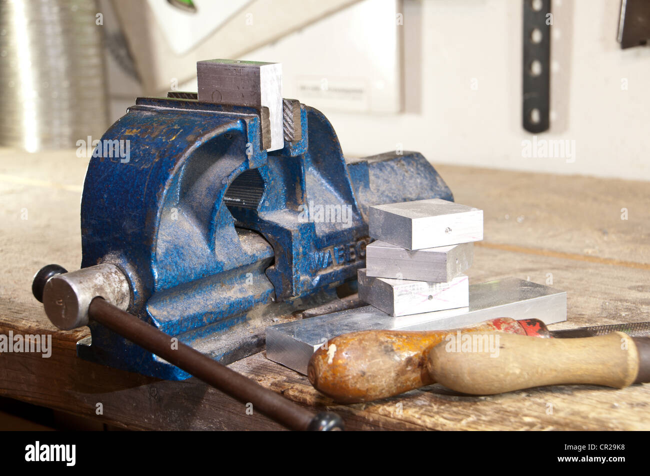 Vice with a block of metal on a wooden workbench Stock Photo - Alamy