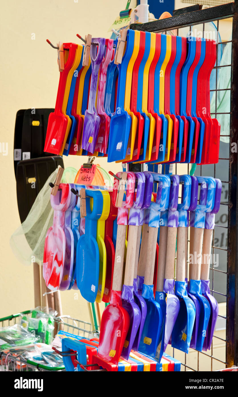 Brightly coloured childrens' sea side spades hanging on a rack Stock ...