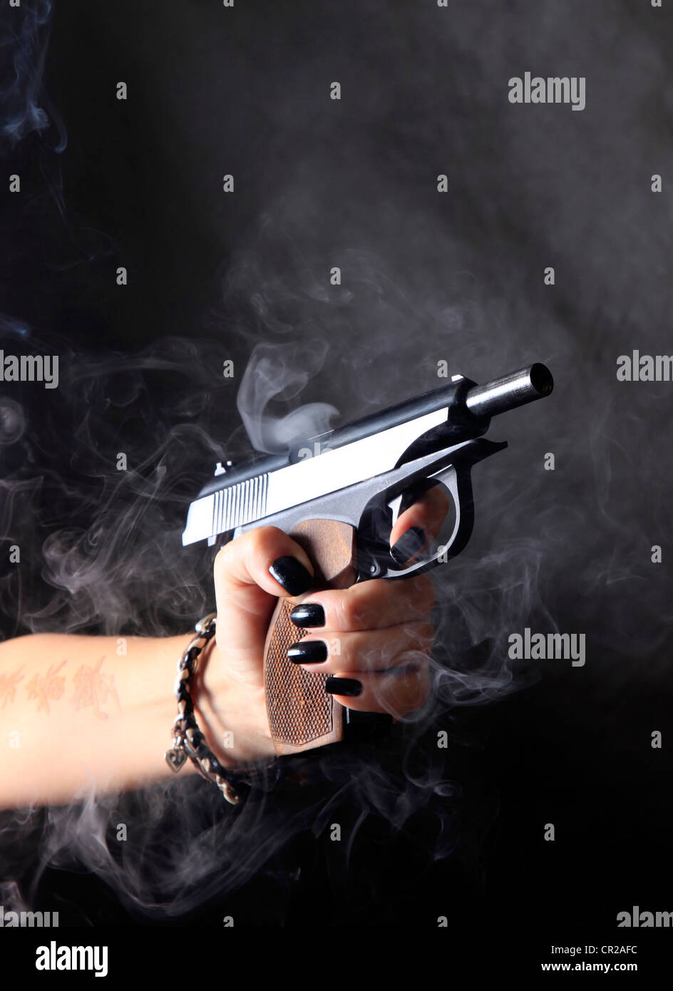 Black pistol in female hand on a background of a smoke Stock Photo - Alamy