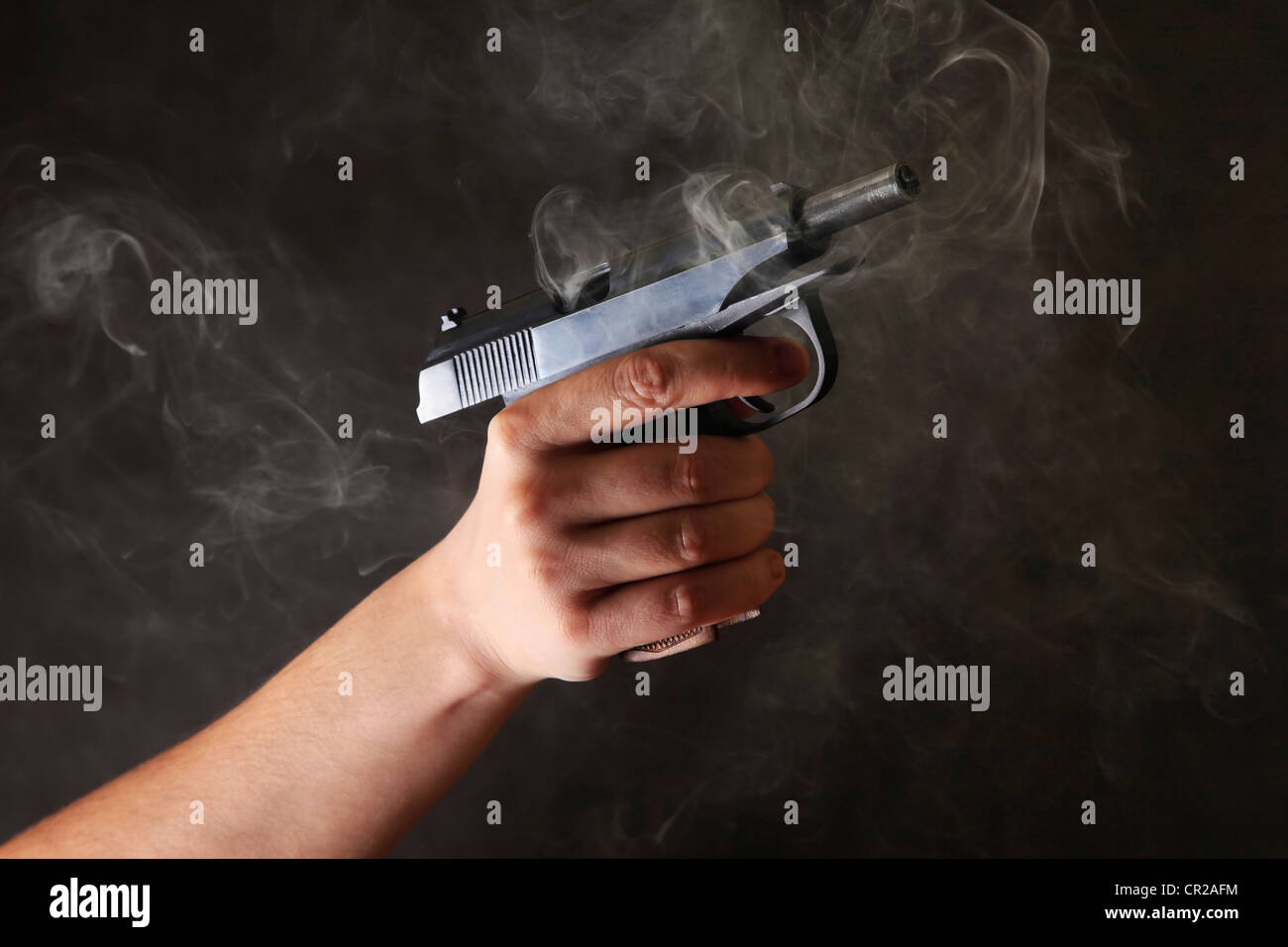 Man's hand a pistol on a dark background with a smoke Stock Photo - Alamy