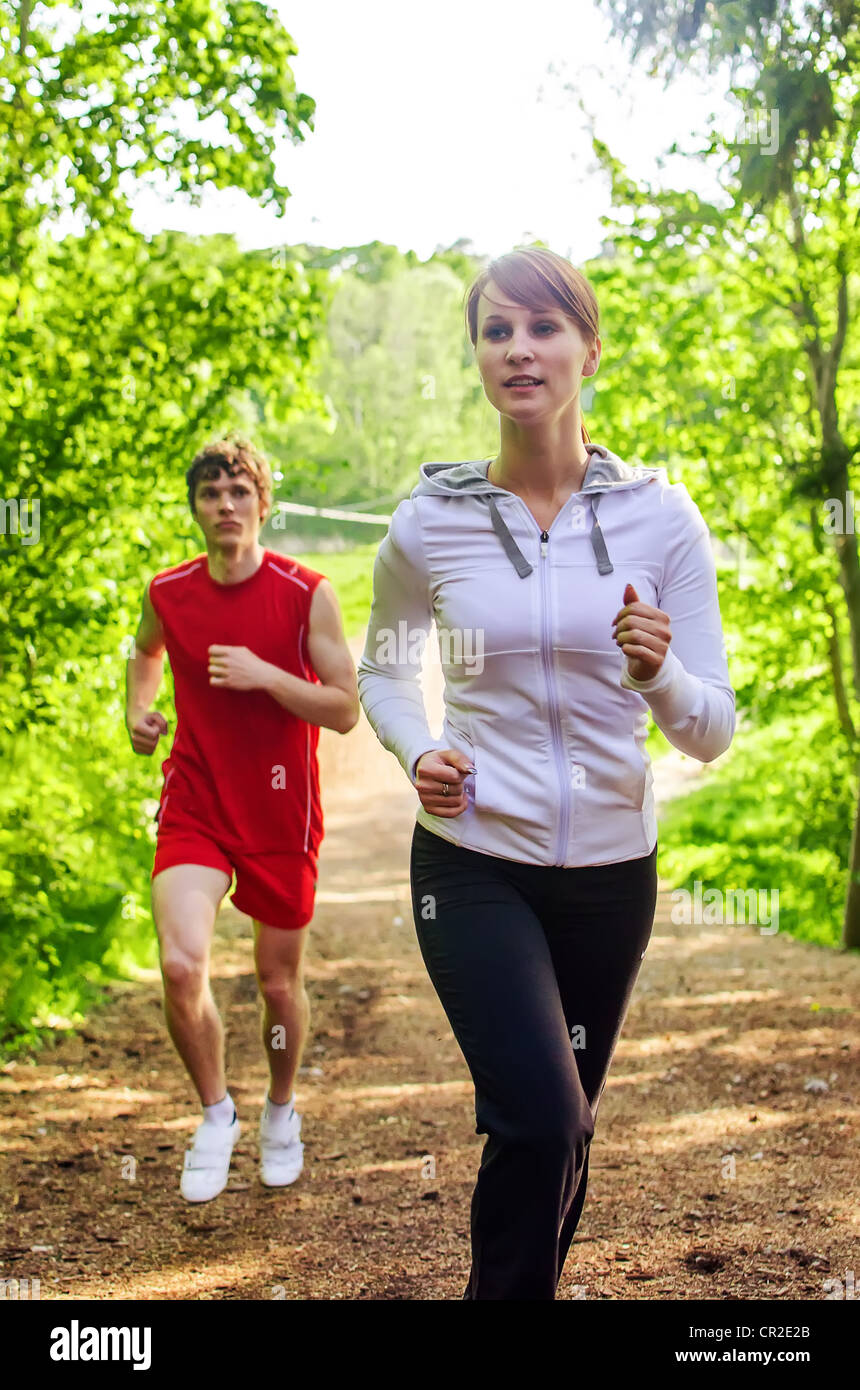 Man and woman running along the forest path Stock Photo - Alamy