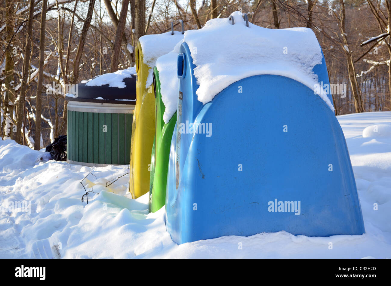 Waste sorting containers covered with snow during winter. Paper, glass ...
