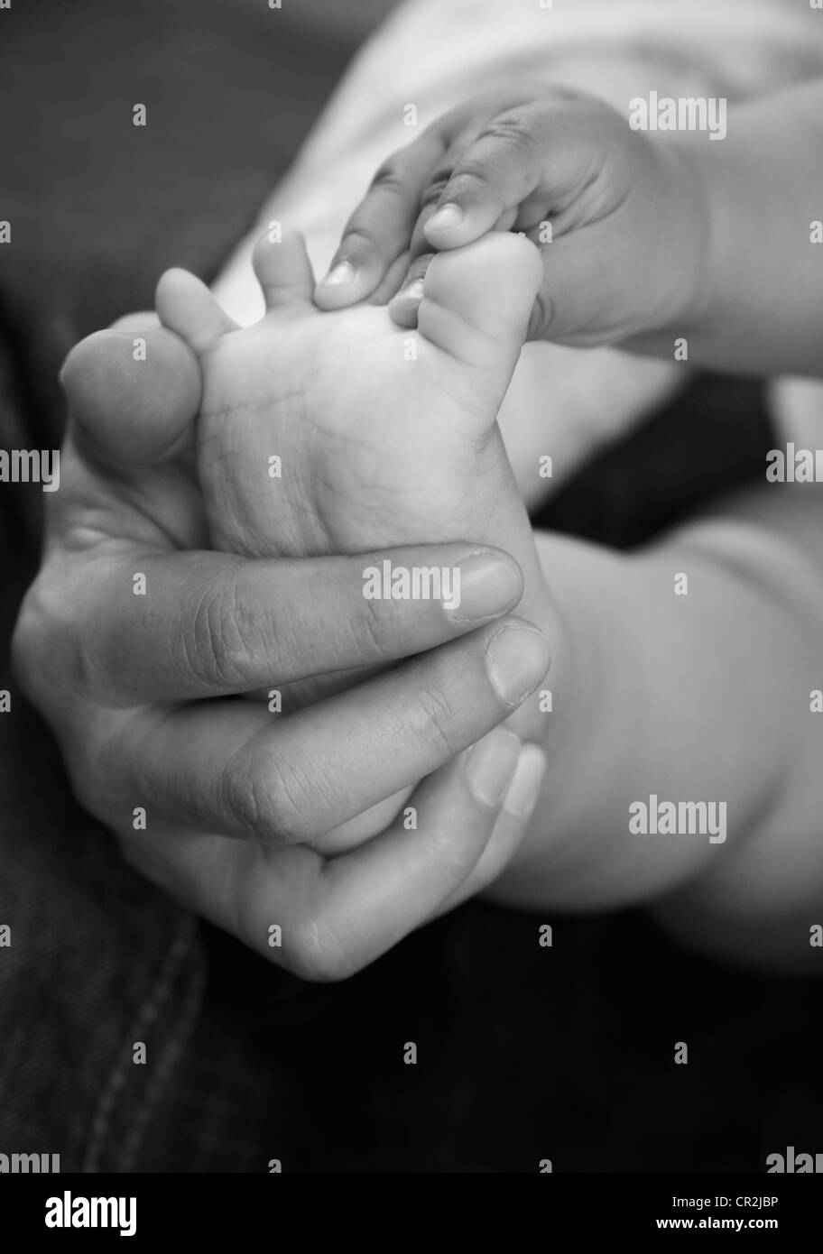 Parents hands hold baby boy legs Stock Photo - Alamy