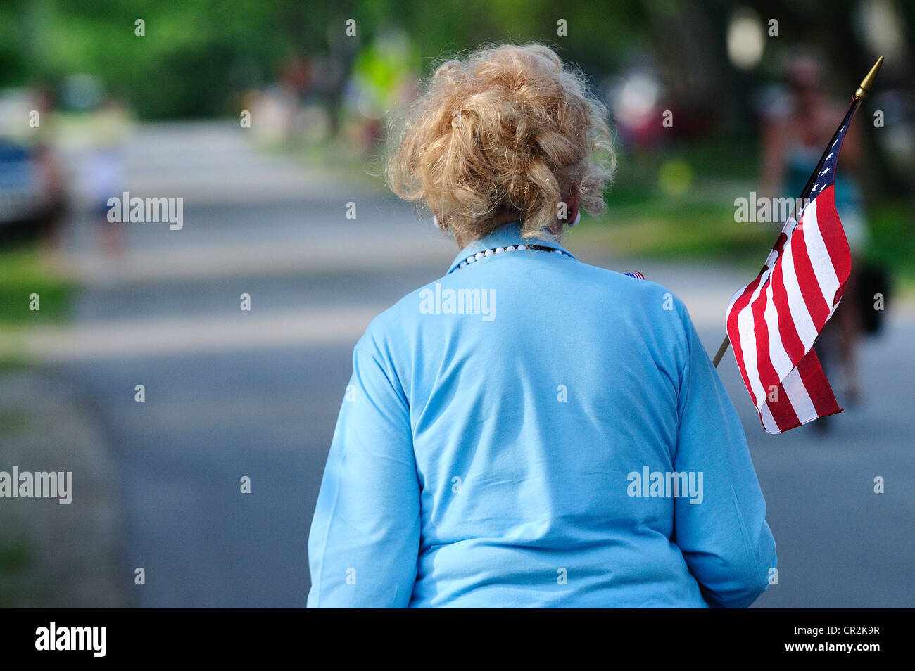 An elderly woman carrying an American flag walks home alone after ...