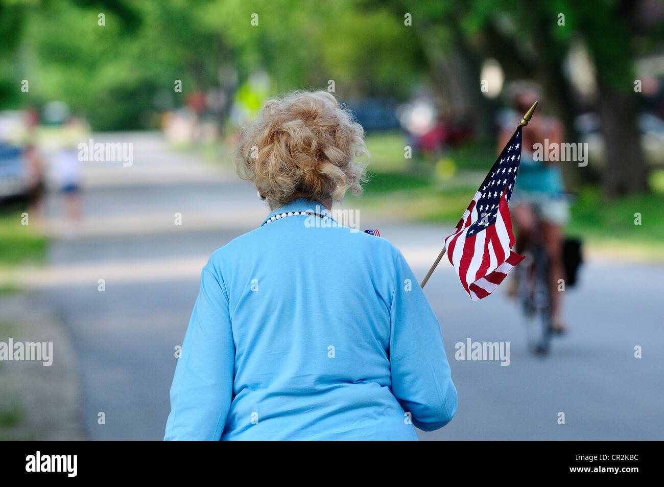 An elderly woman carrying an American flag walks home alone after ...