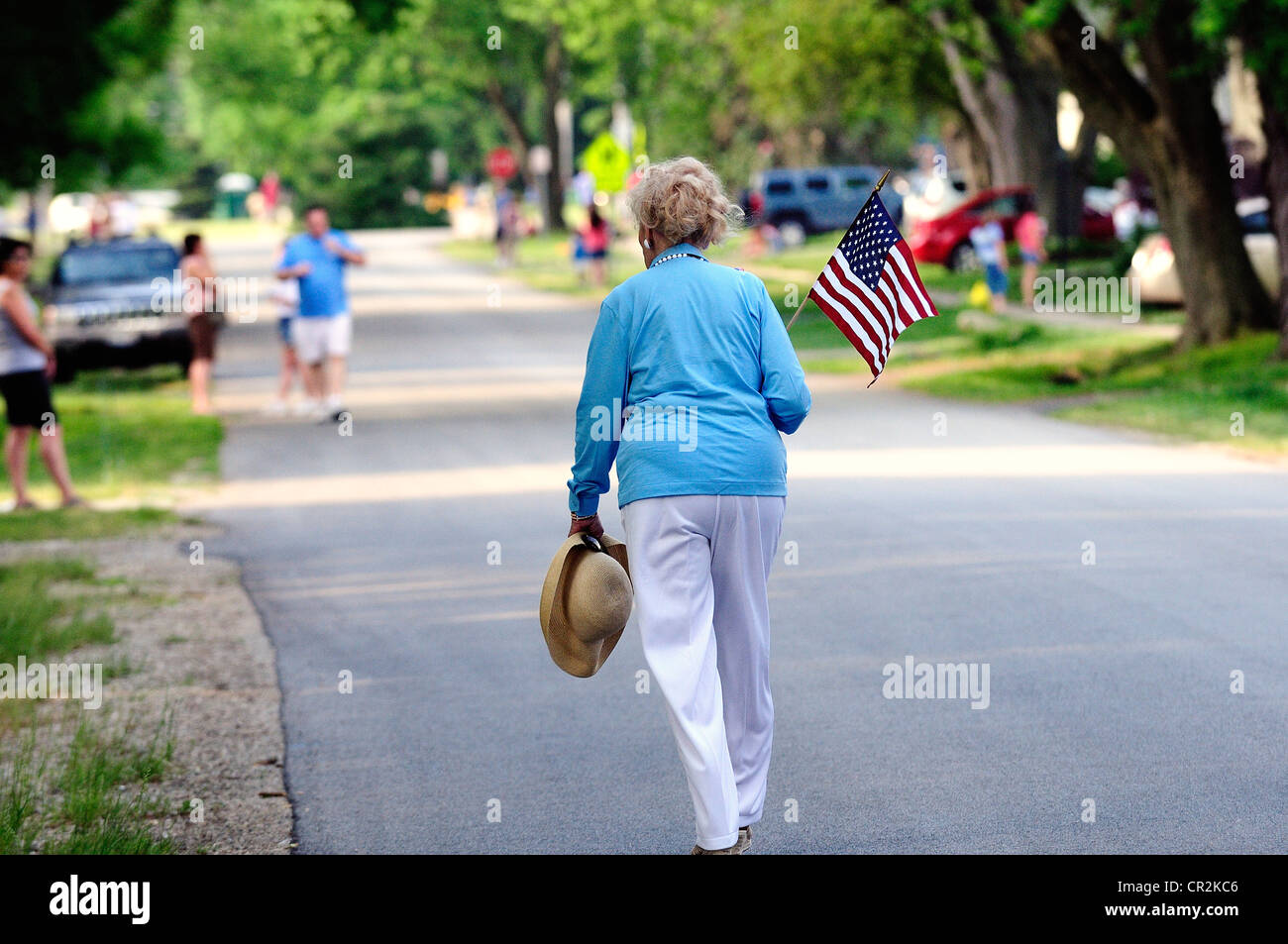 An elderly woman carrying an American flag walks home alone after ...