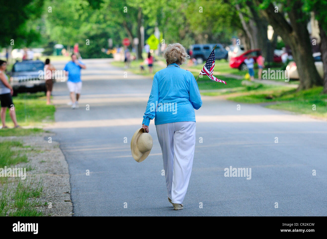 An elderly woman carrying an American flag walks home alone after ...