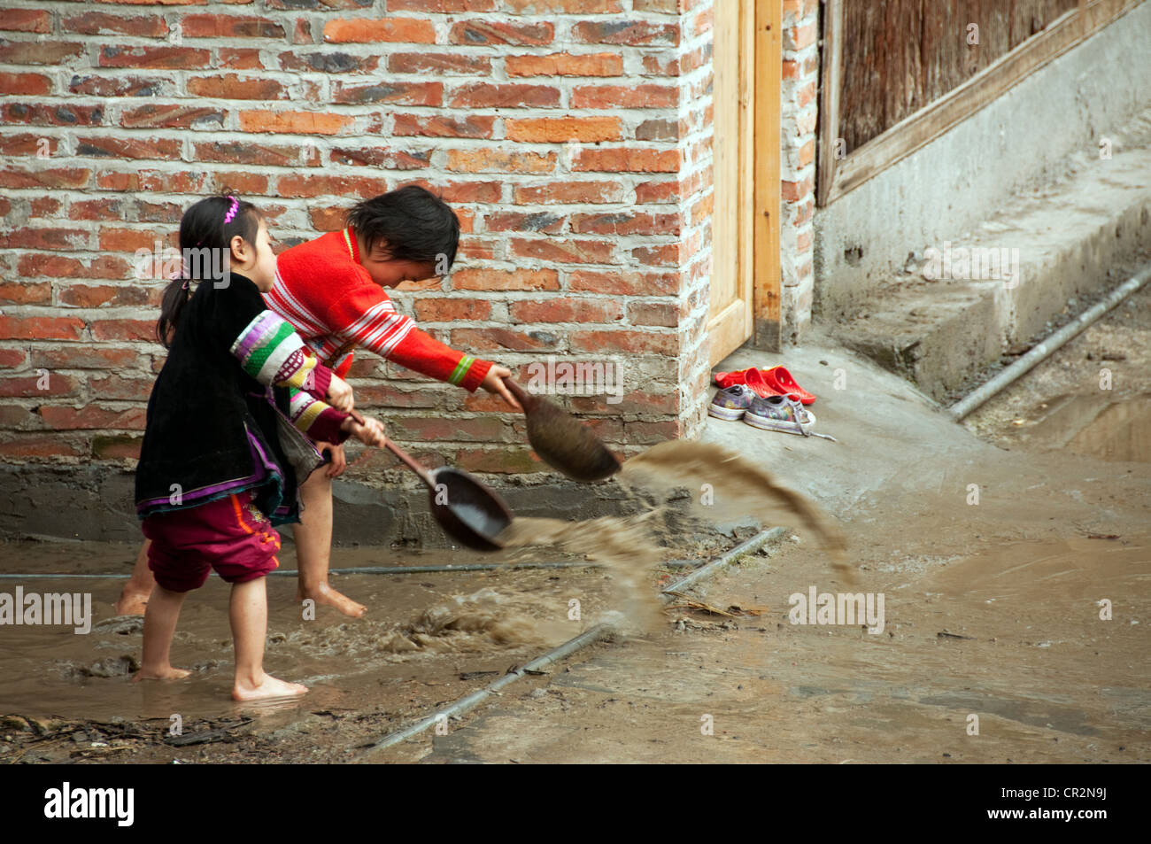 Two Chinese kids emptying a puddle with pans, Gaozheng Dong Village ...