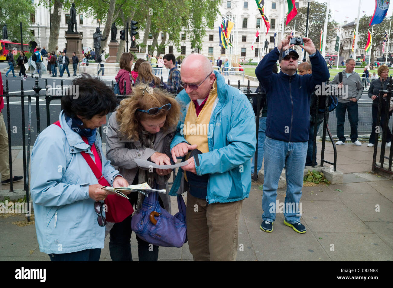 A group of tourists looking at maps while another takes pictures ...