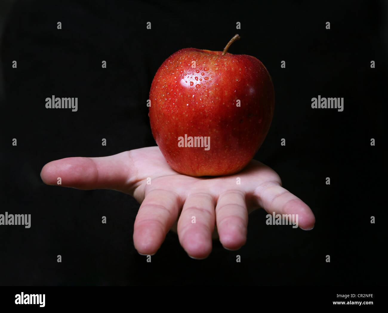 Man's hand with a red apple on a dark background Stock Photo - Alamy
