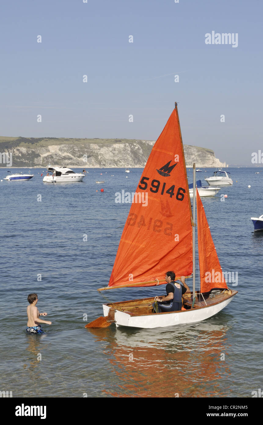 A young boy helps his father with a sailing dinghy at Swanage, Dorset ...